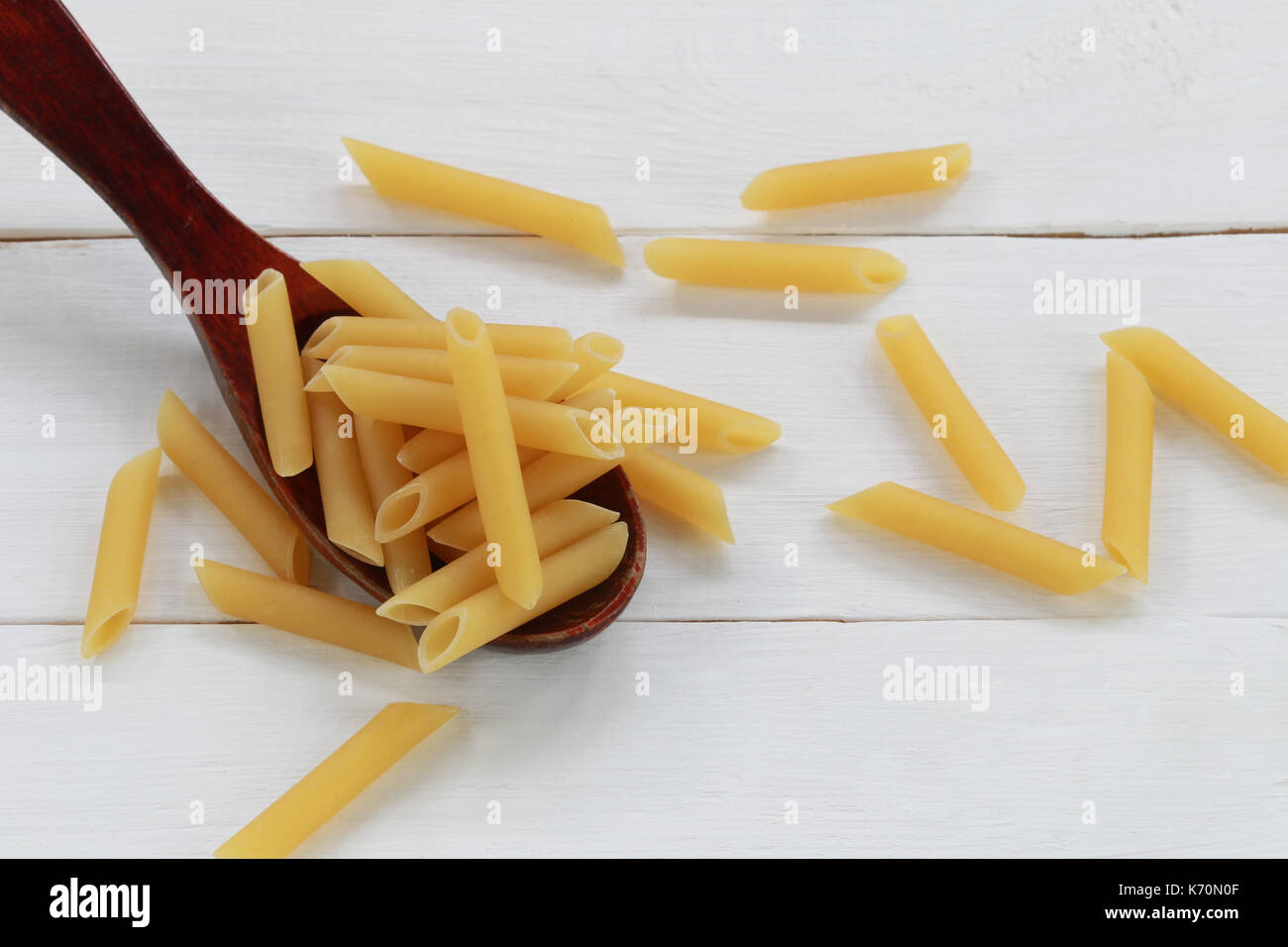 Raw Macaroni in the wooden spoon on wood background for design in your ...