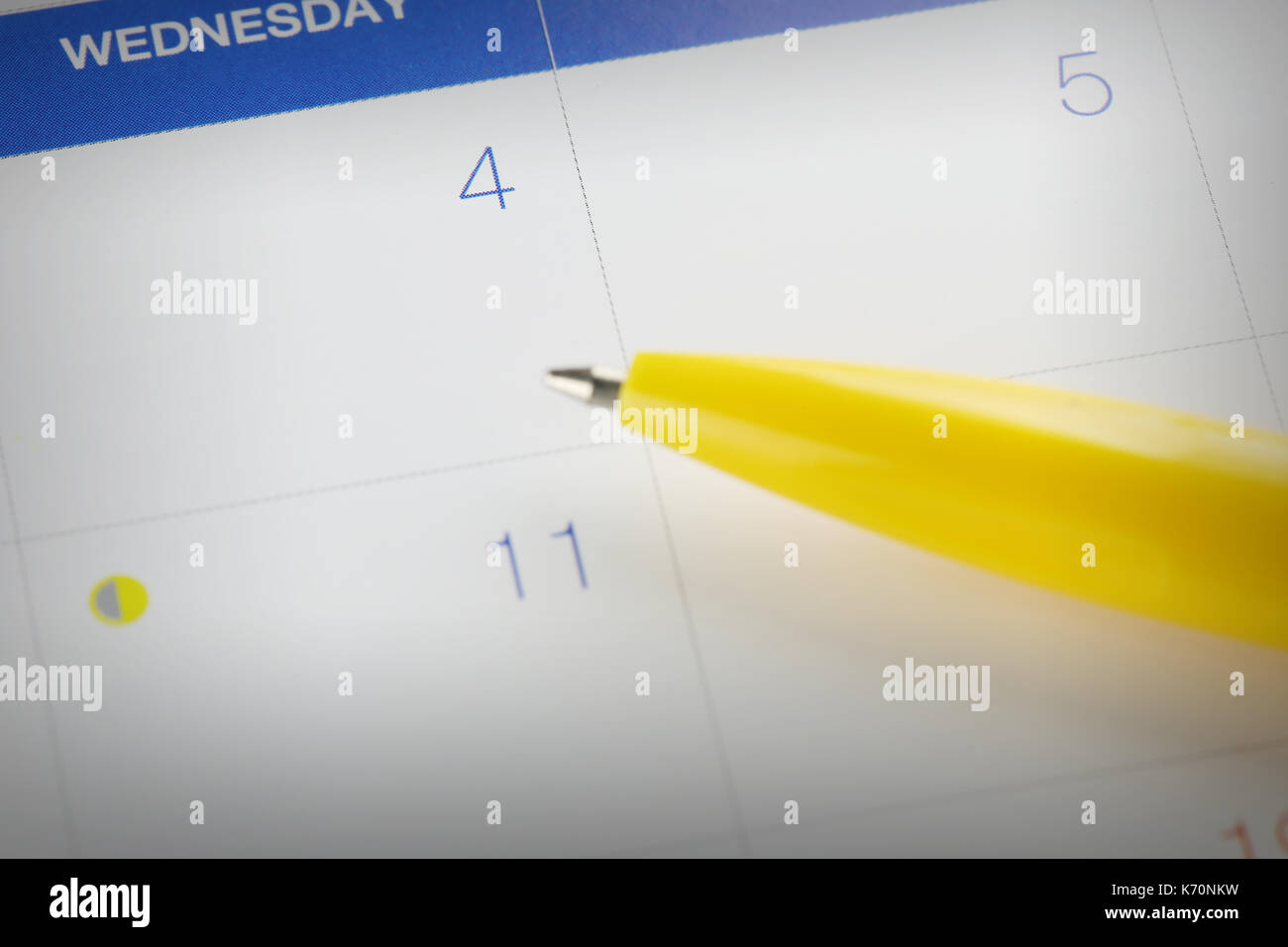 yellow pen points to the number 4 on calendar background in concept of ...