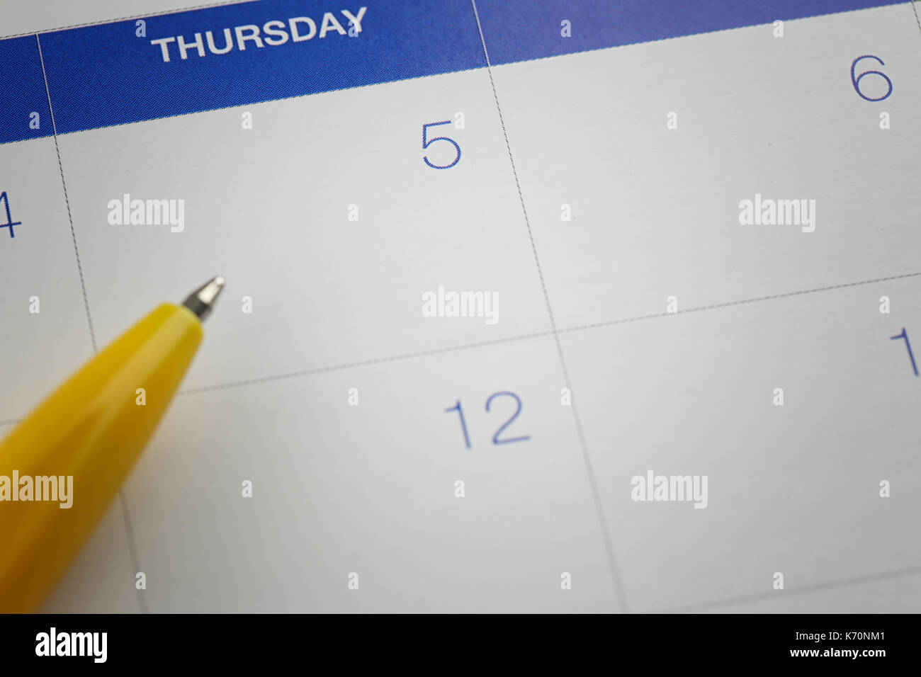yellow pen points to the number 5 on calendar background in concept of ...