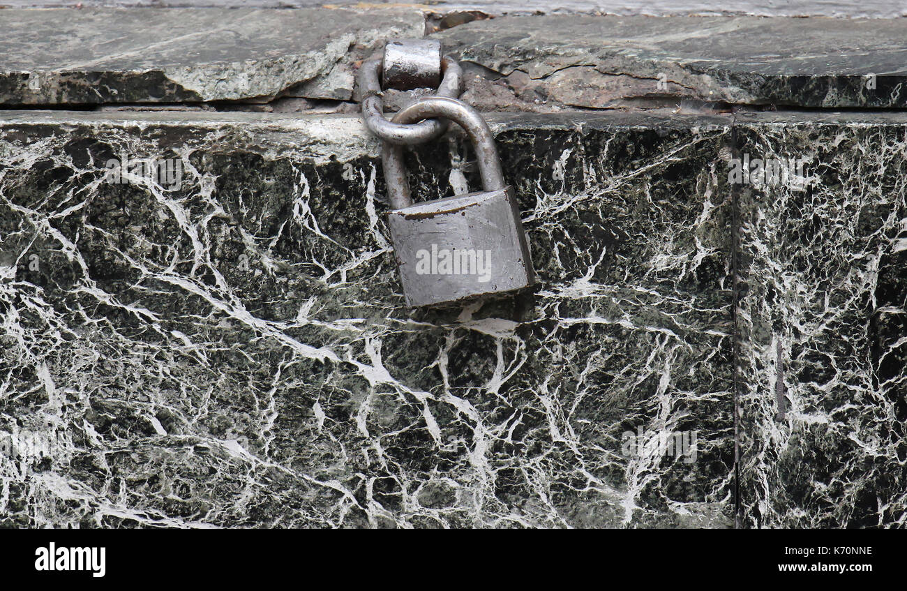 Old metal padlock securing marble stone lid Stock Photo - Alamy