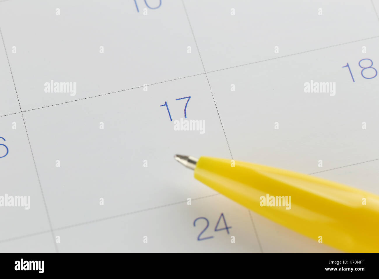 yellow pen points to the number 17 on calendar background in concept of ...