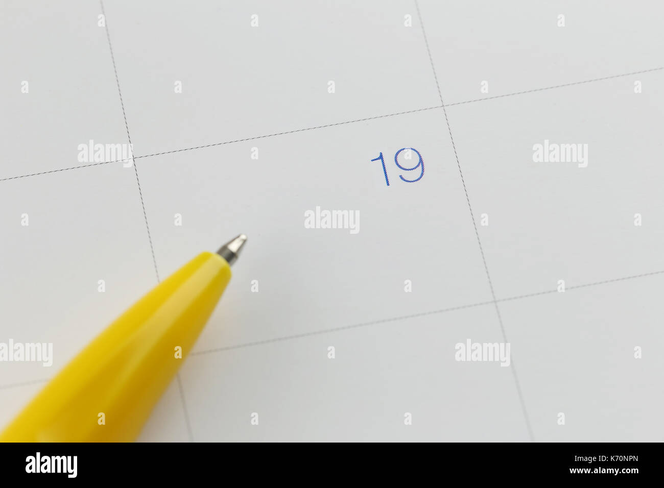 yellow pen points to the number 19 on calendar background in concept of ...