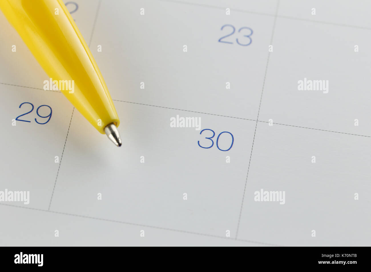 yellow pen points to the number 30 on calendar background in concept of ...