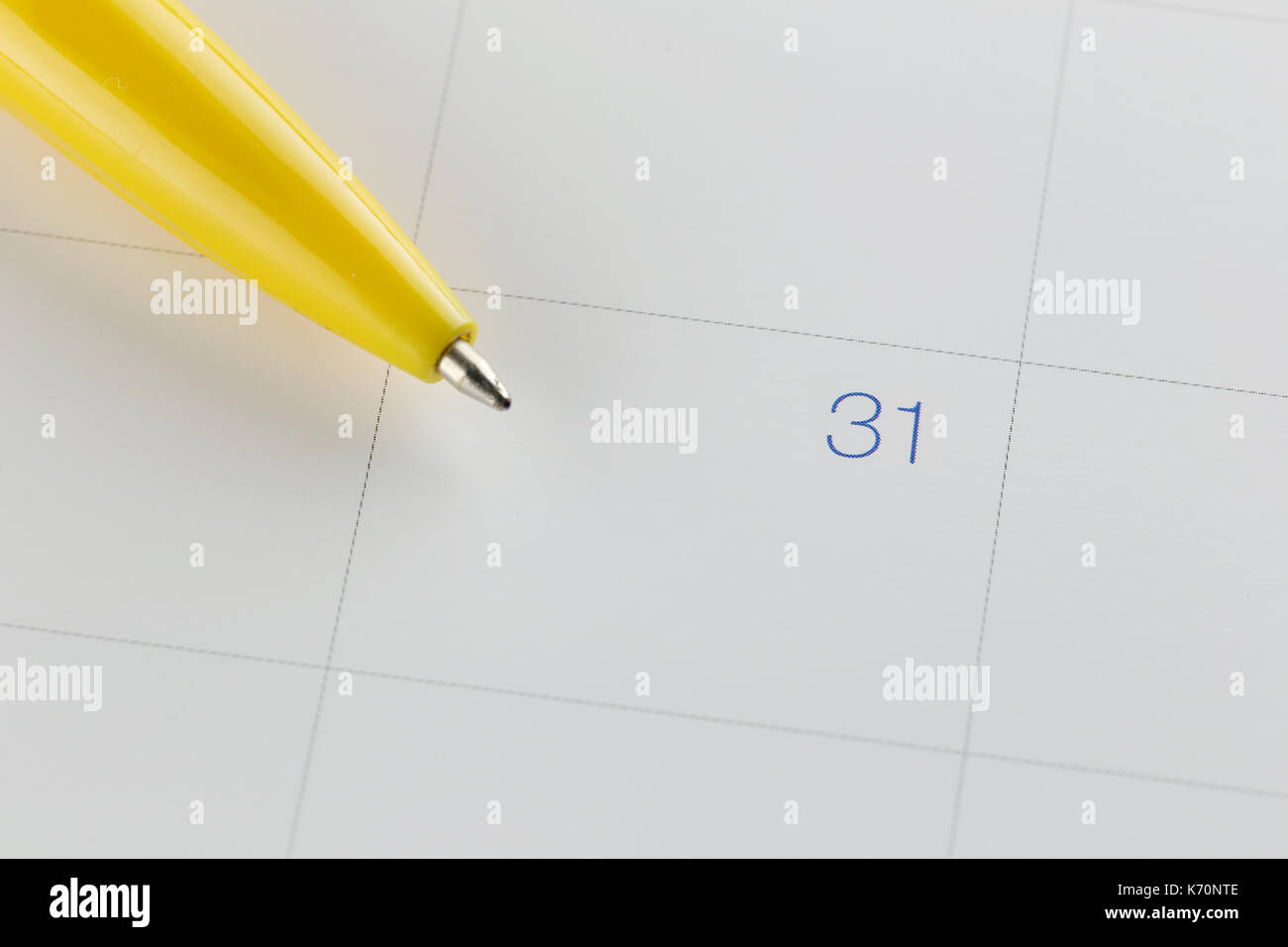 yellow pen points to the number 31 on calendar background in concept of ...
