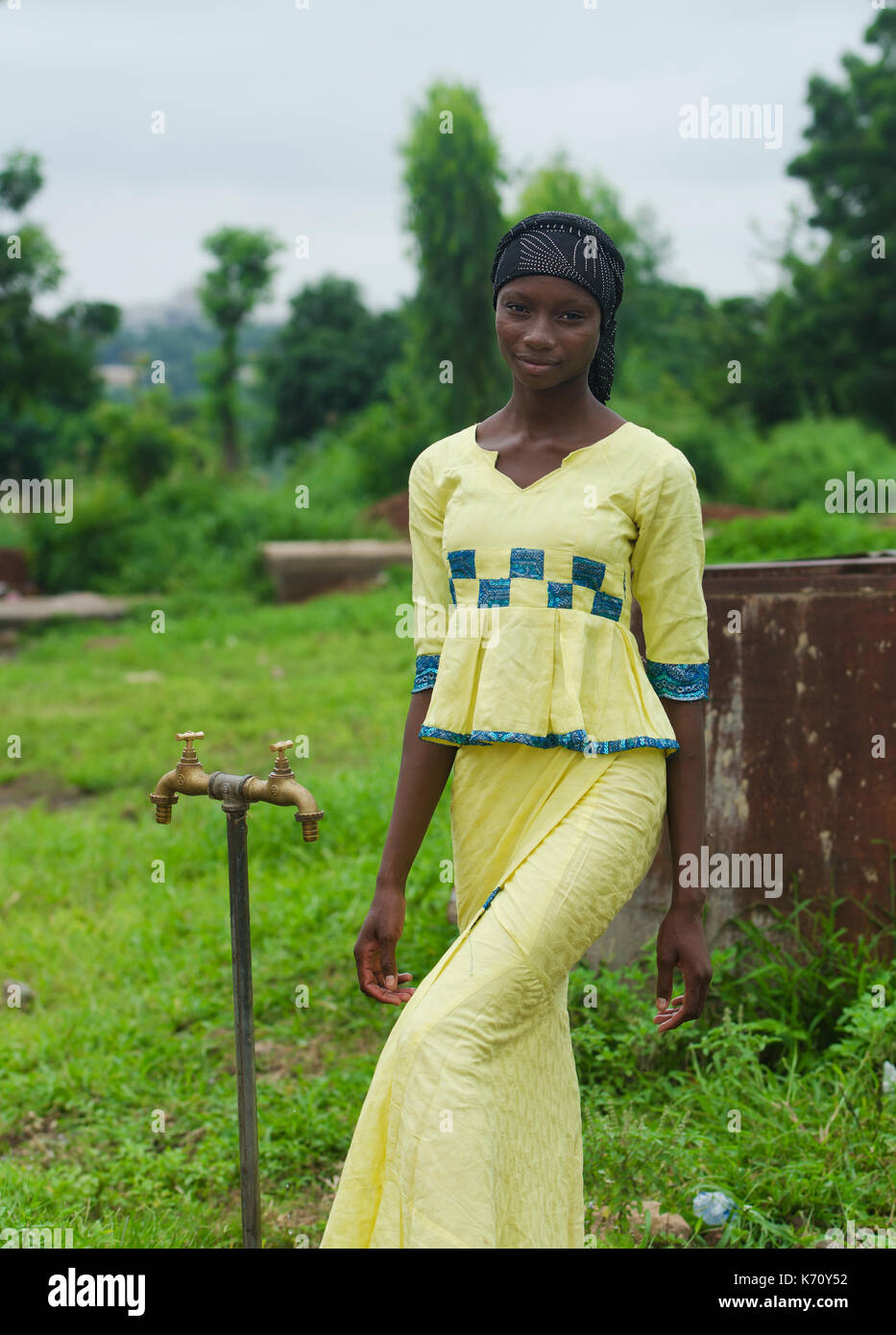 Full body shot of African black girl standing next to water tap in ...