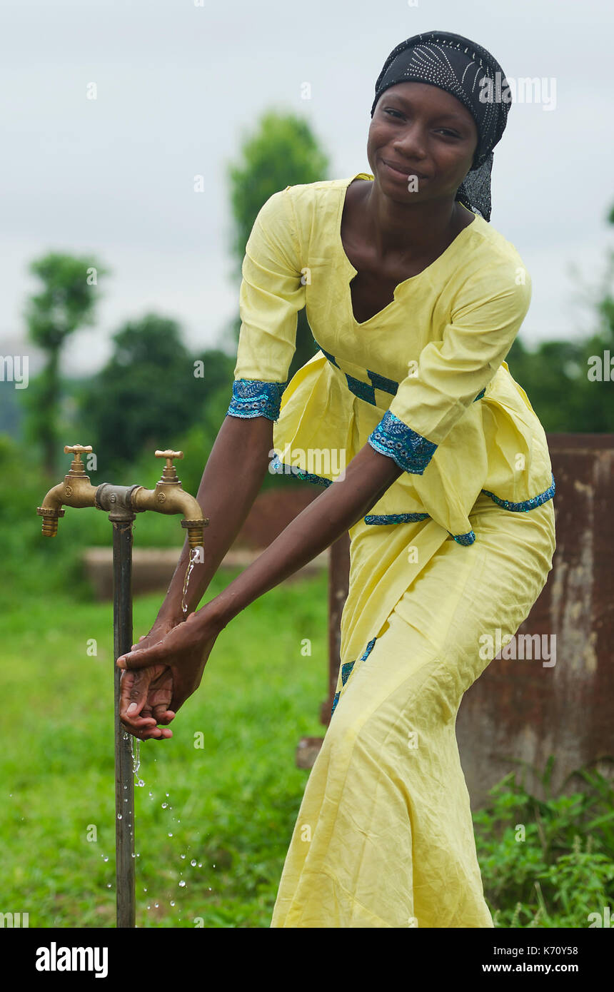 Standing gorgeous African girl washing hands outdoors with clean water ...