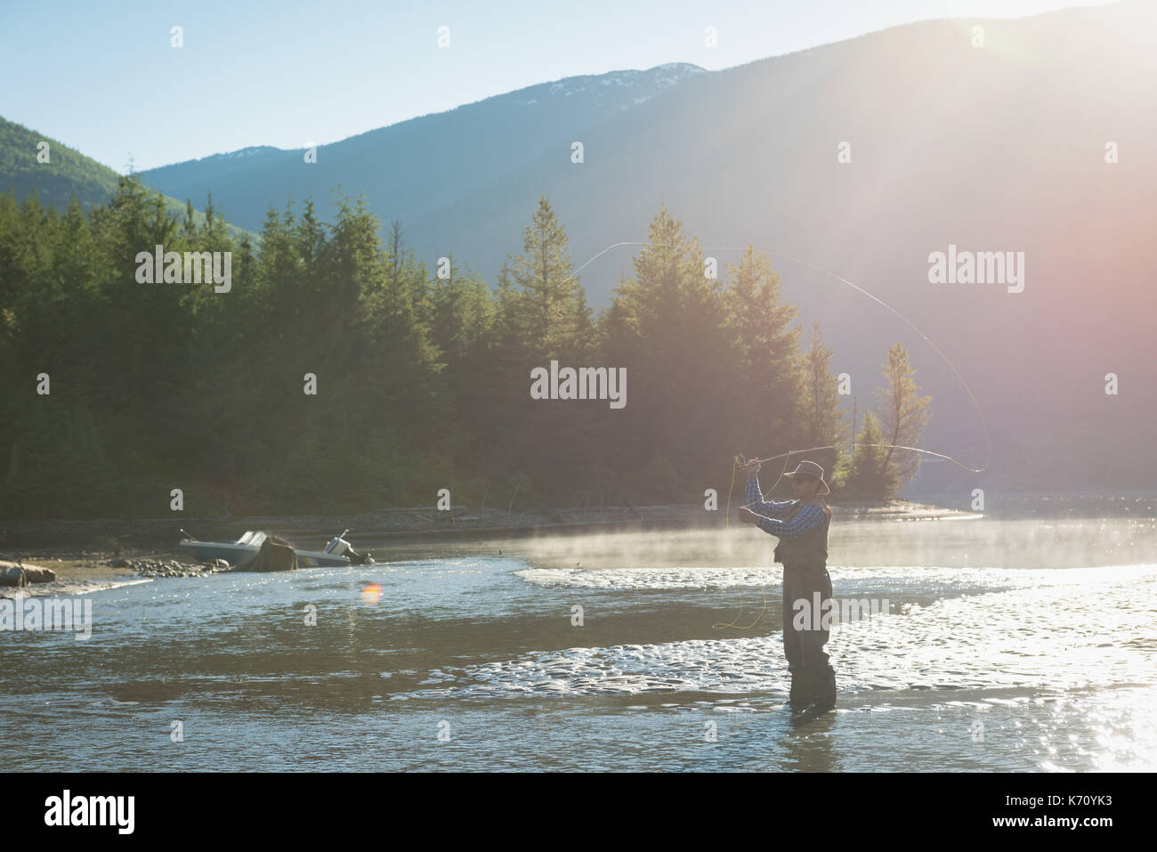 Side view of man casting fishing rod during fishing in river against ...