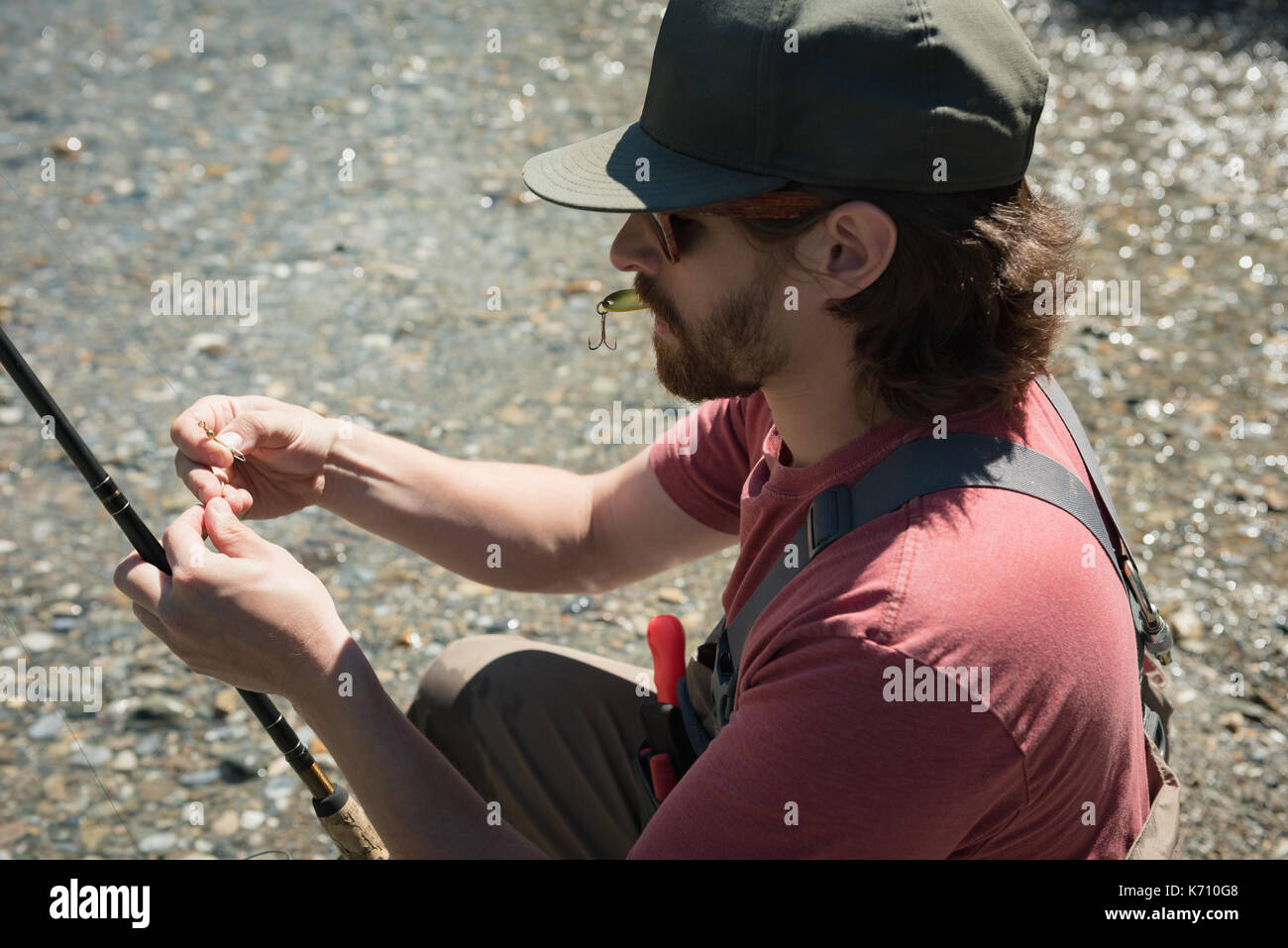 High angle view of man holding fishing hook and rod while crouching at ...