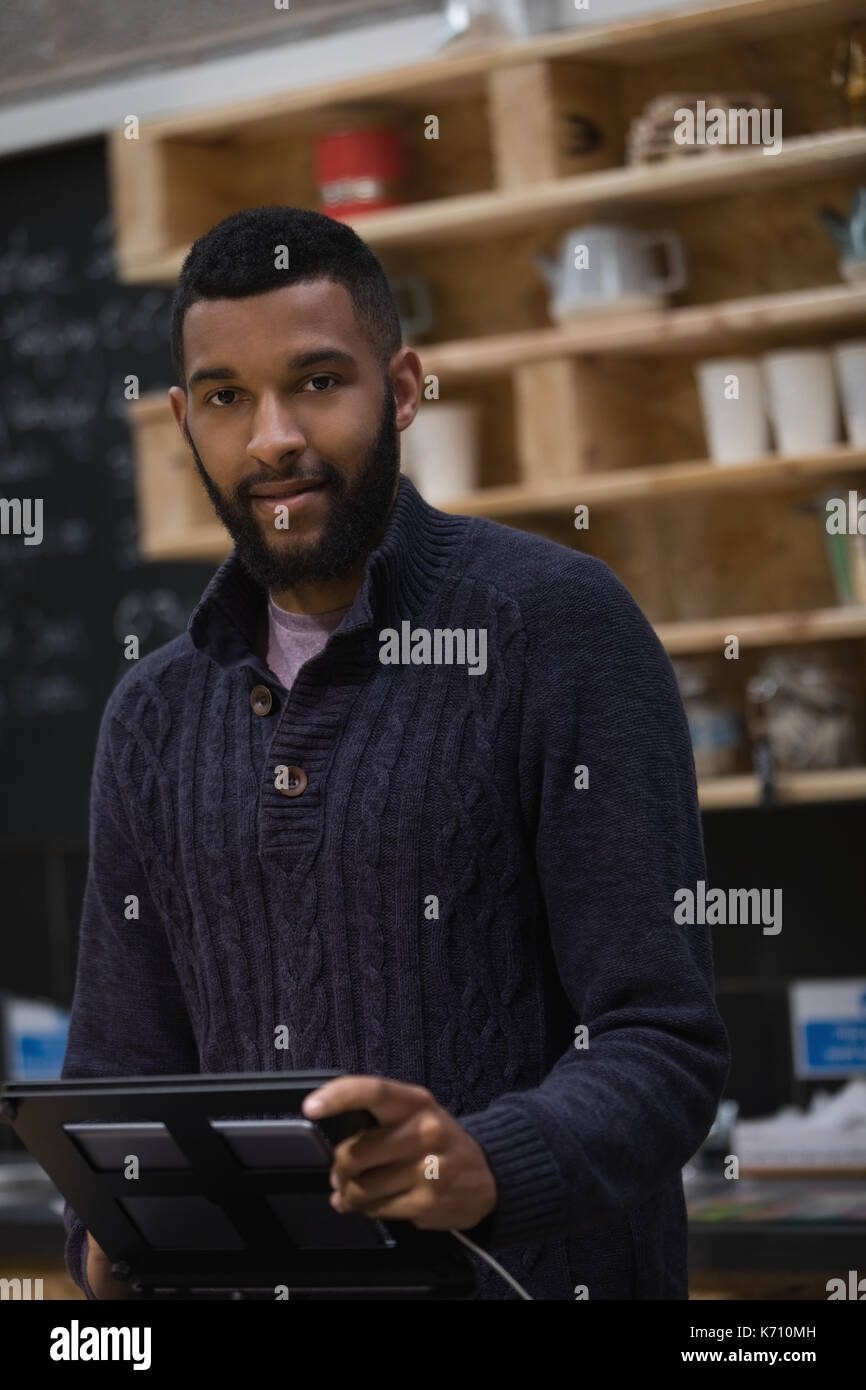 Portrait of owner using computer while standing at bar counter in cafe ...