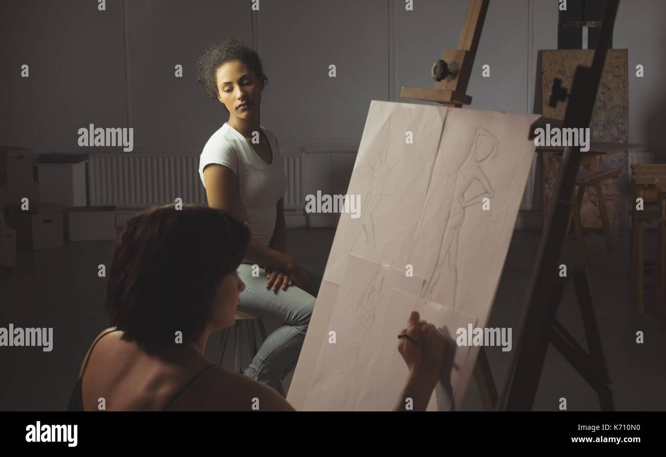 Female artist drawing a sketch of woman on canvas in art studio Stock ...