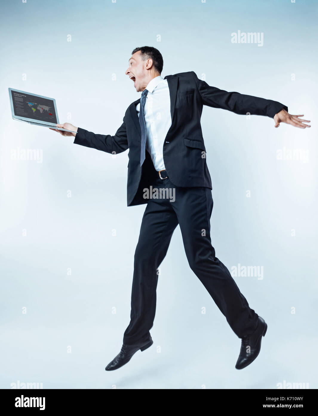 Excited man of business jumping with laptop over background Stock Photo ...