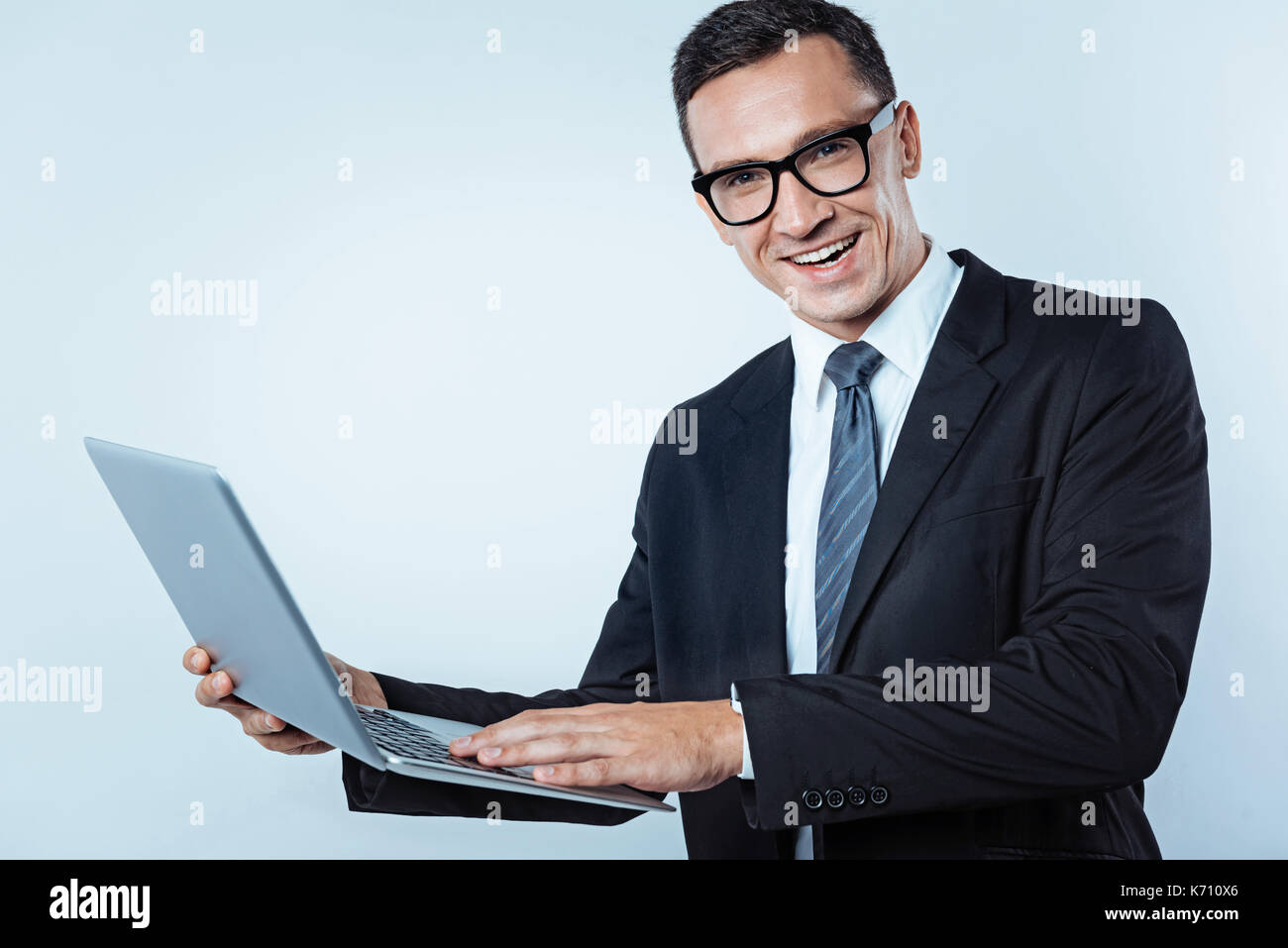 Smart man with laptop beaming into camera Stock Photo - Alamy