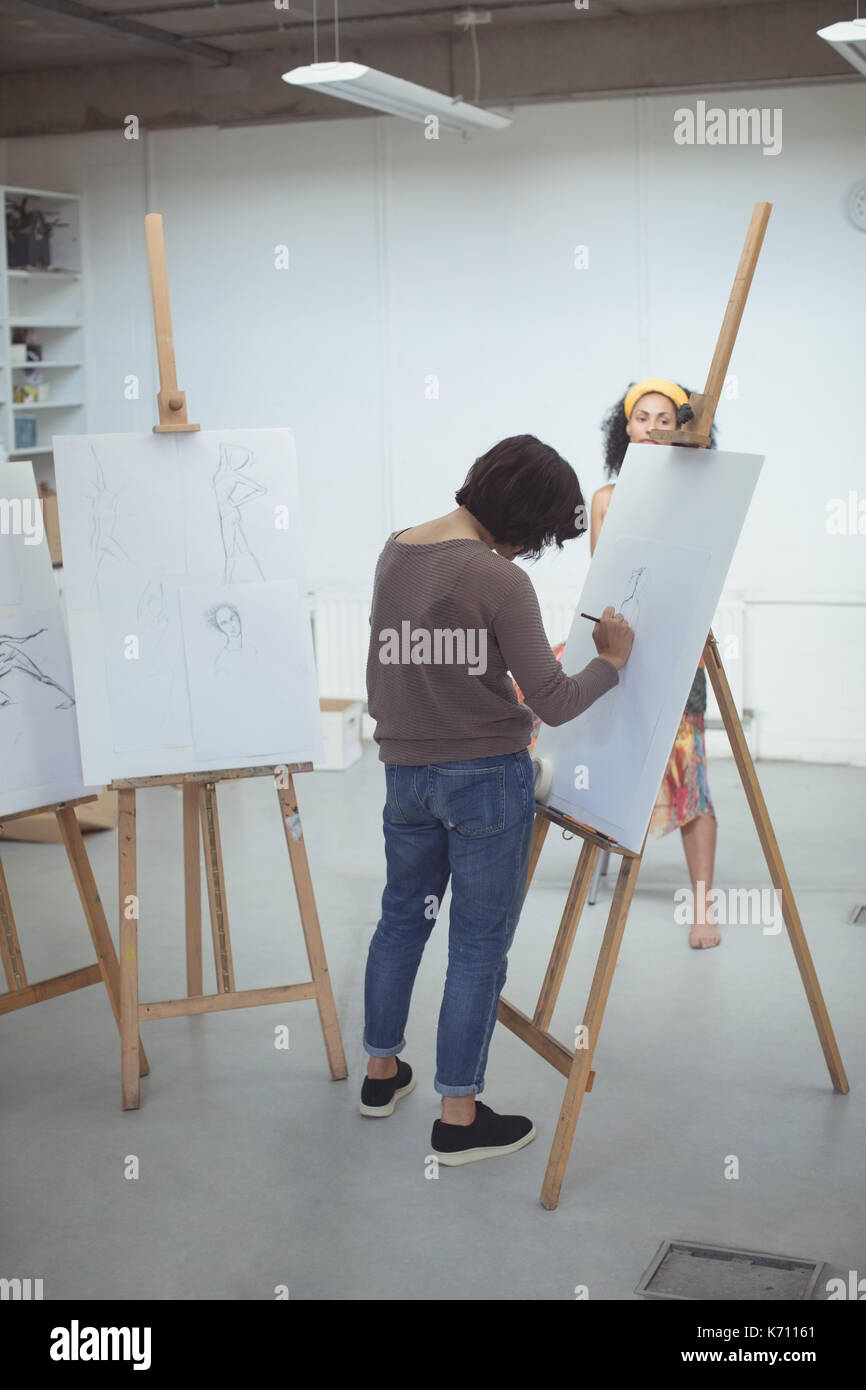 Female artist drawing a sketch of woman on canvas in art studio Stock ...