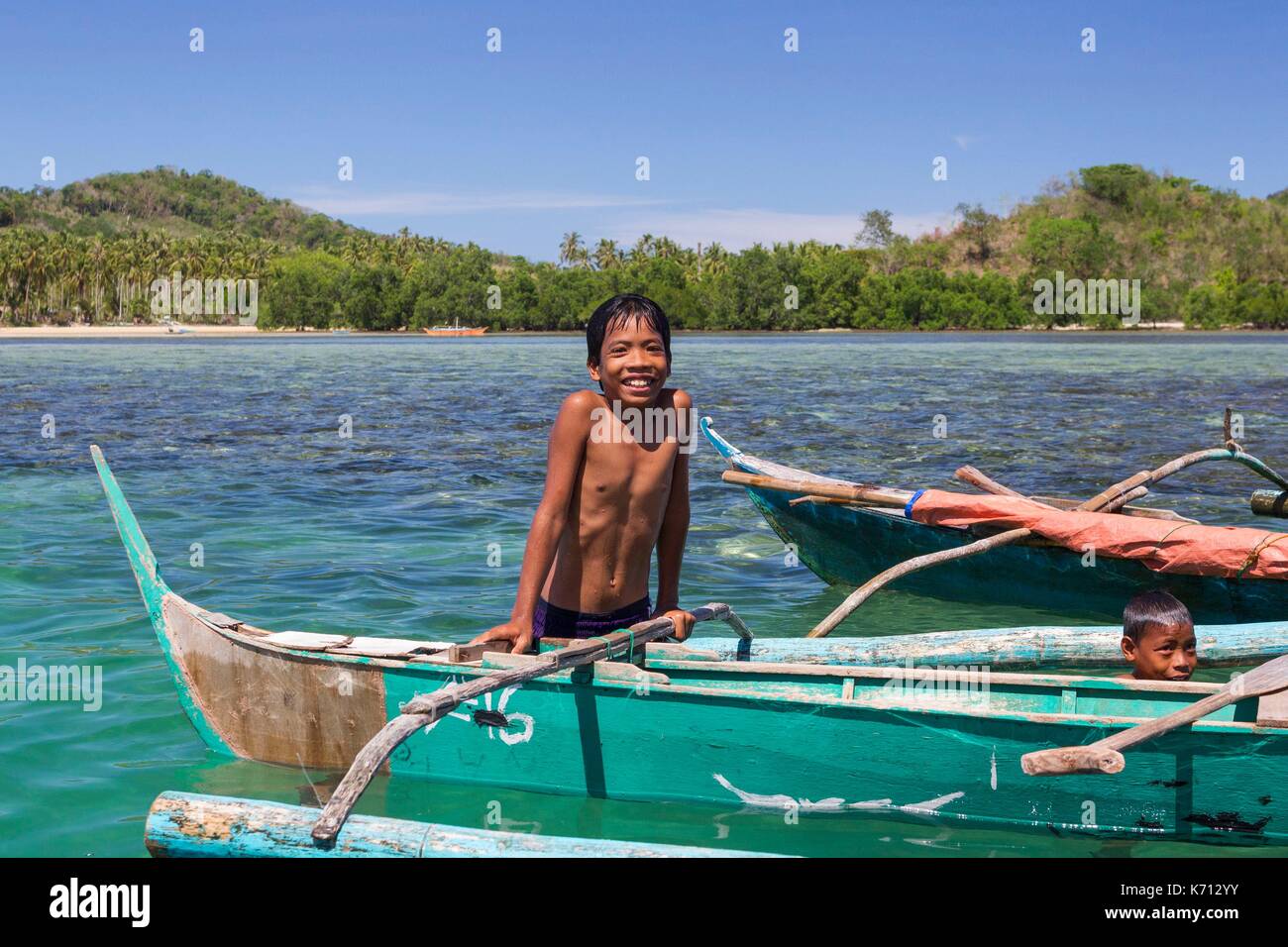 Philippines, Palawan, Dumaran Island, smiling boy playing in water ...