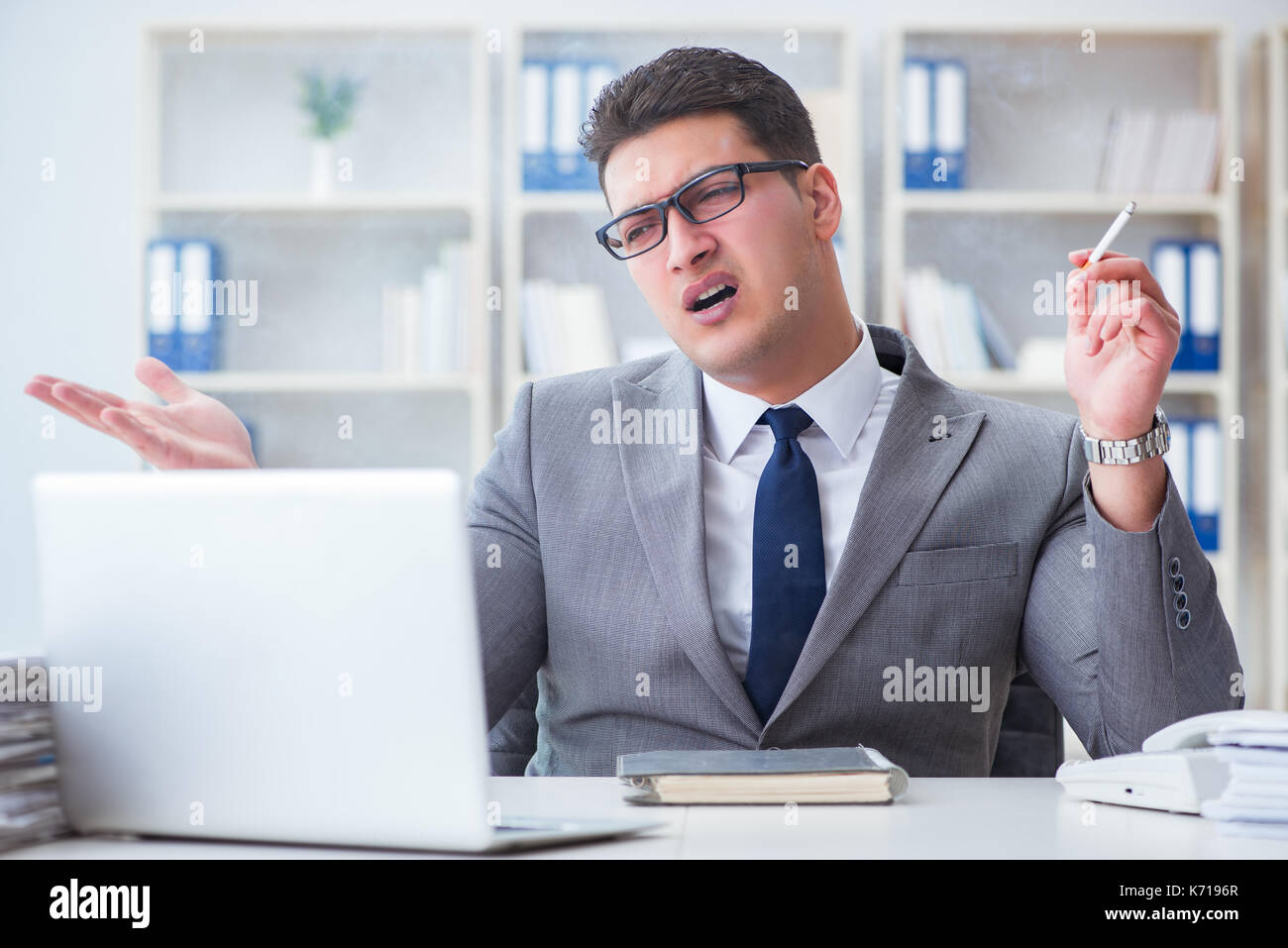 Businessman smoking in office at work Stock Photo - Alamy