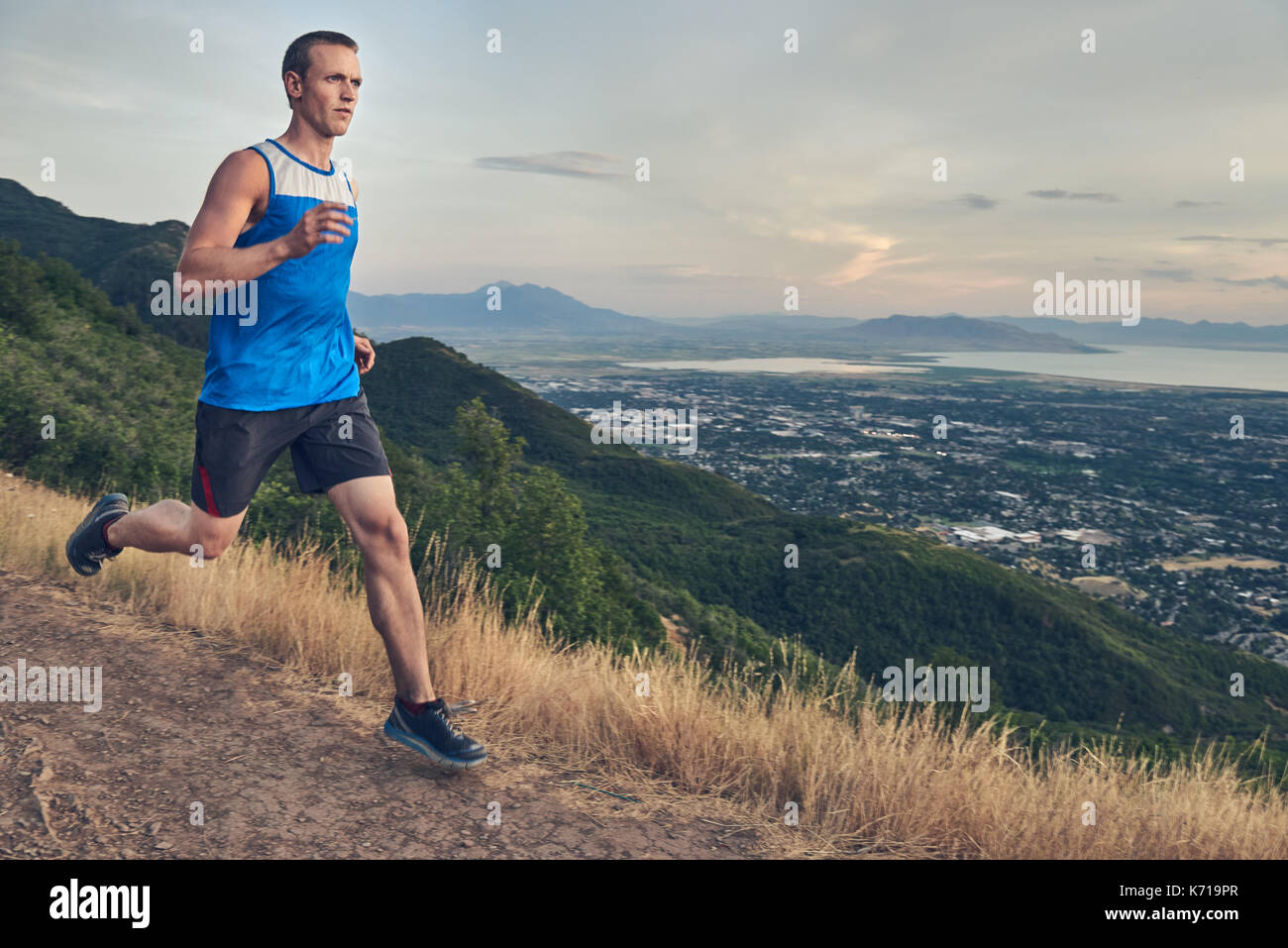 Man running on trail in mountains with city in the background Stock ...