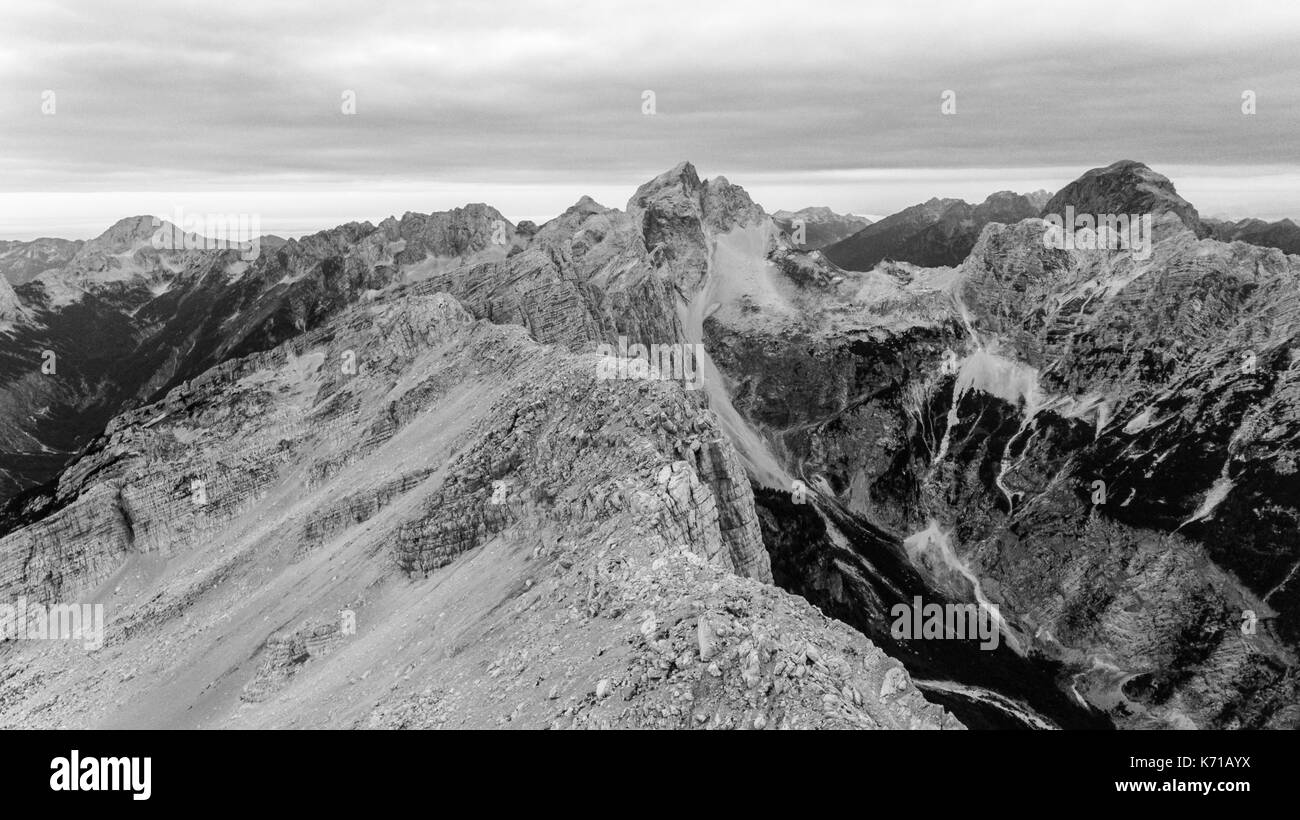 Sheer mountain cliff with slope on one side Stock Photo - Alamy
