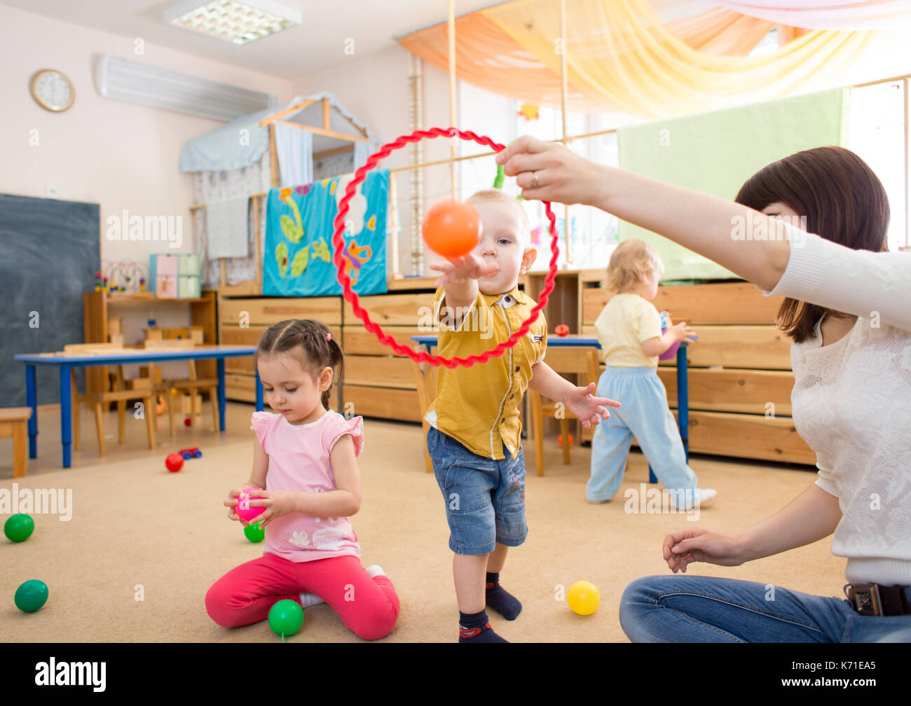 Happy children playing with ball and ring in kindergarten Stock Photo ...