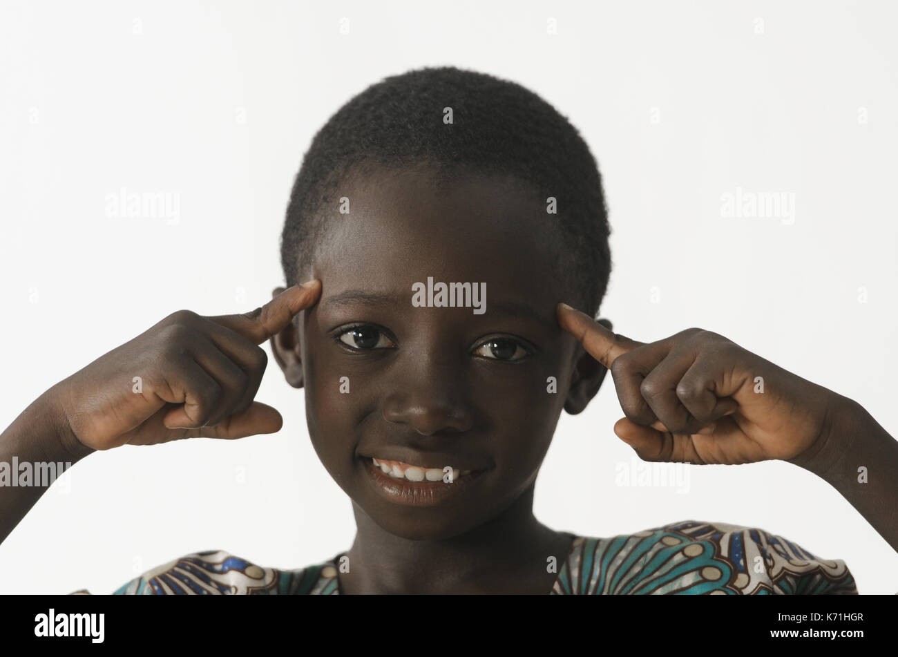 African ethnicity boy thinking with his fingers pointing to his head ...