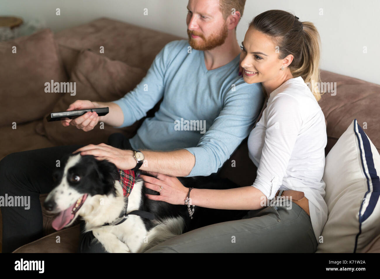 Beautiful couple watching television at home with their dog Stock Photo ...