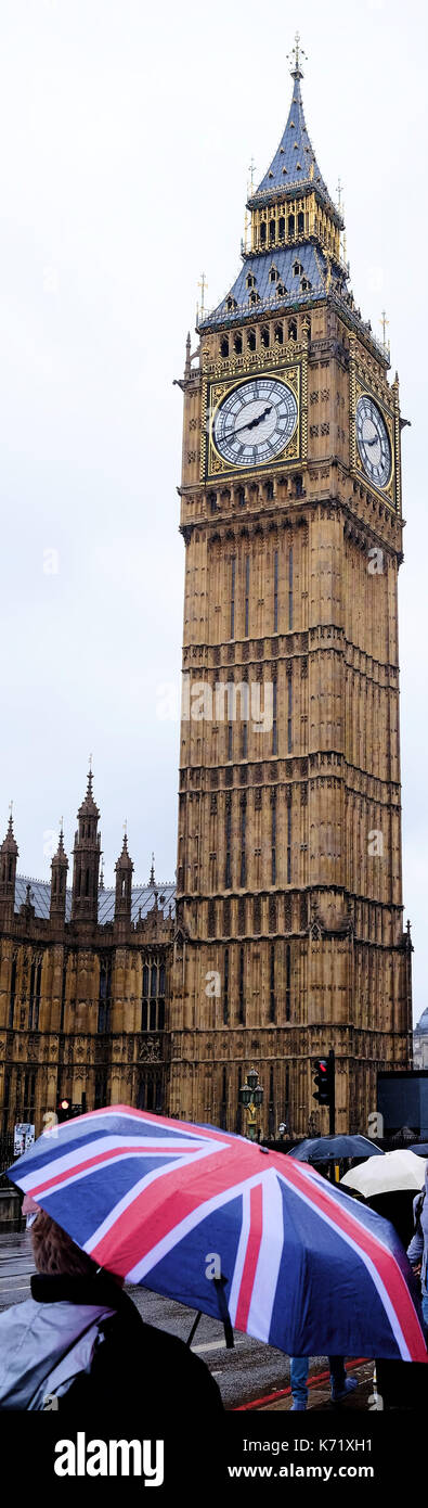 Pedestrian carrying a Union Jack decorated umbrella walking in rain ...