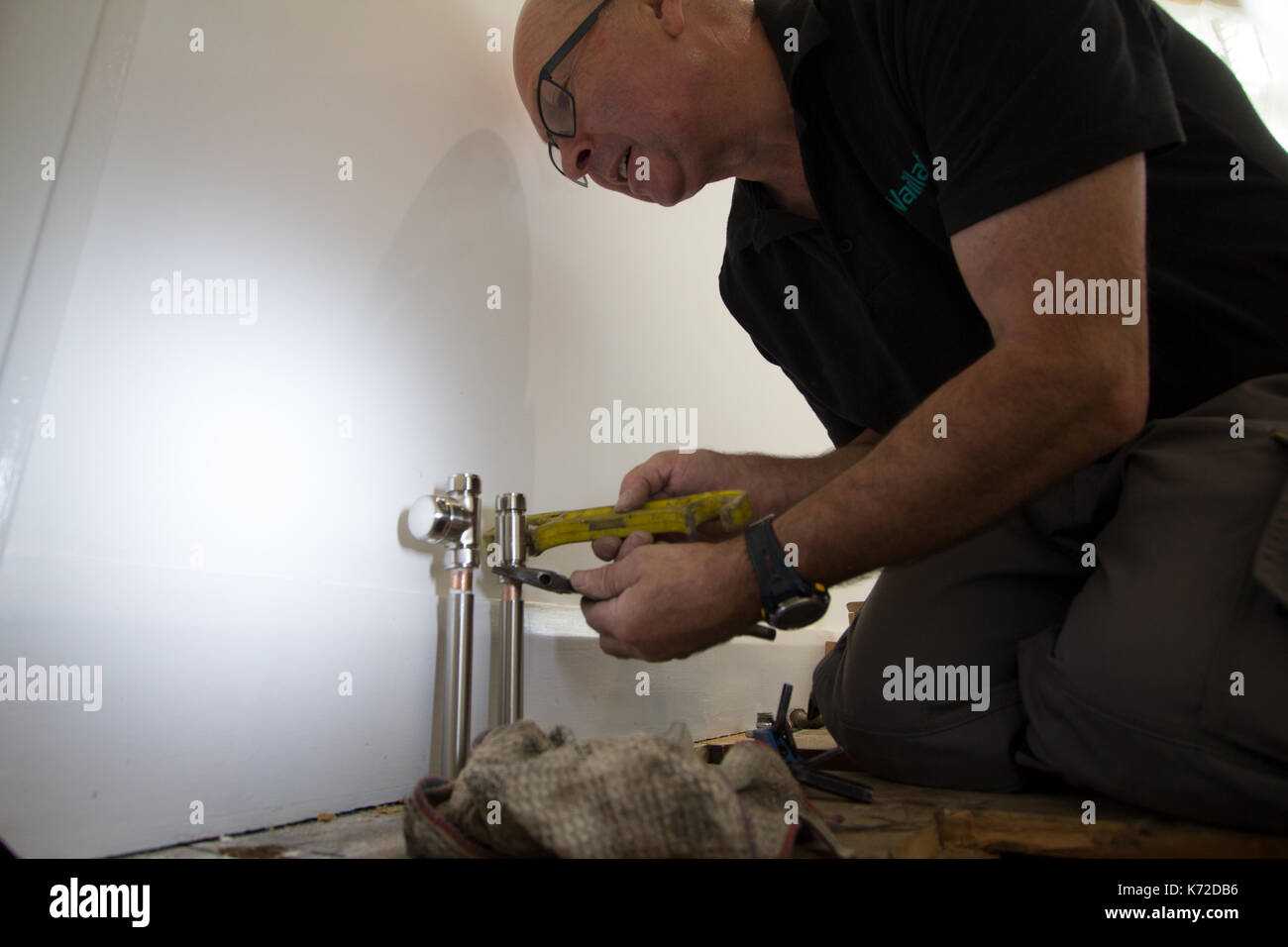 Gas safe qualified plumber fitting radiator in London house Stock Photo ...
