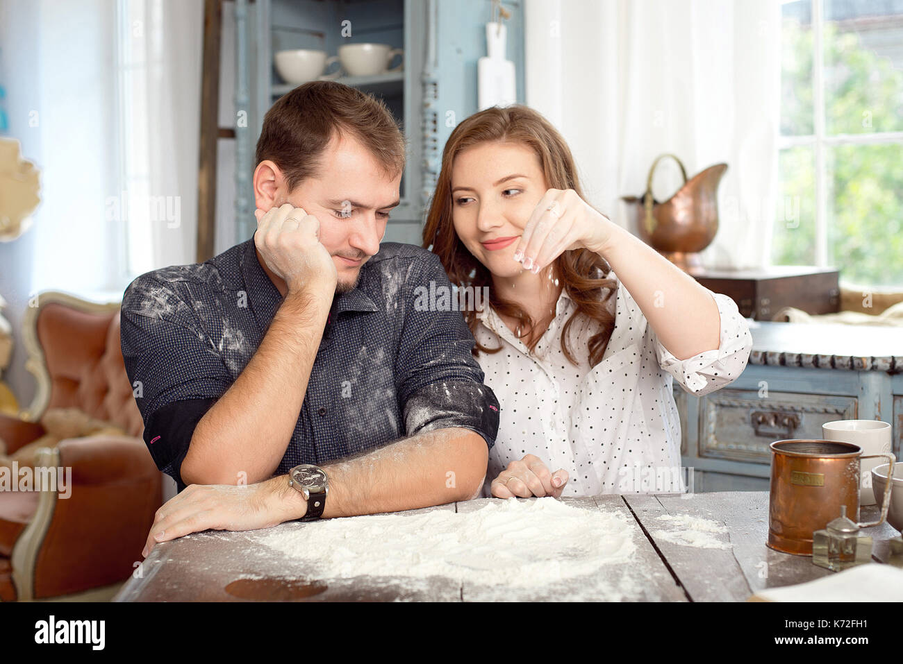 Young couple in the kitchen playing with flour. Funny moments, smiles ...