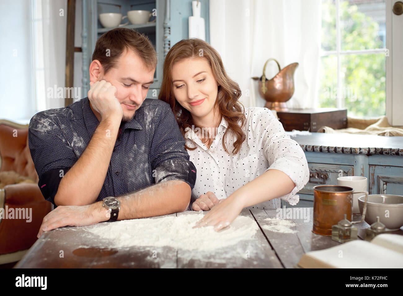 Young couple in the kitchen playing with flour. Funny moments, smiles ...