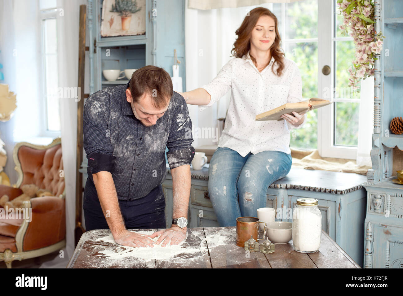 Young couple in the kitchen playing with flour. Funny moments, smiles ...