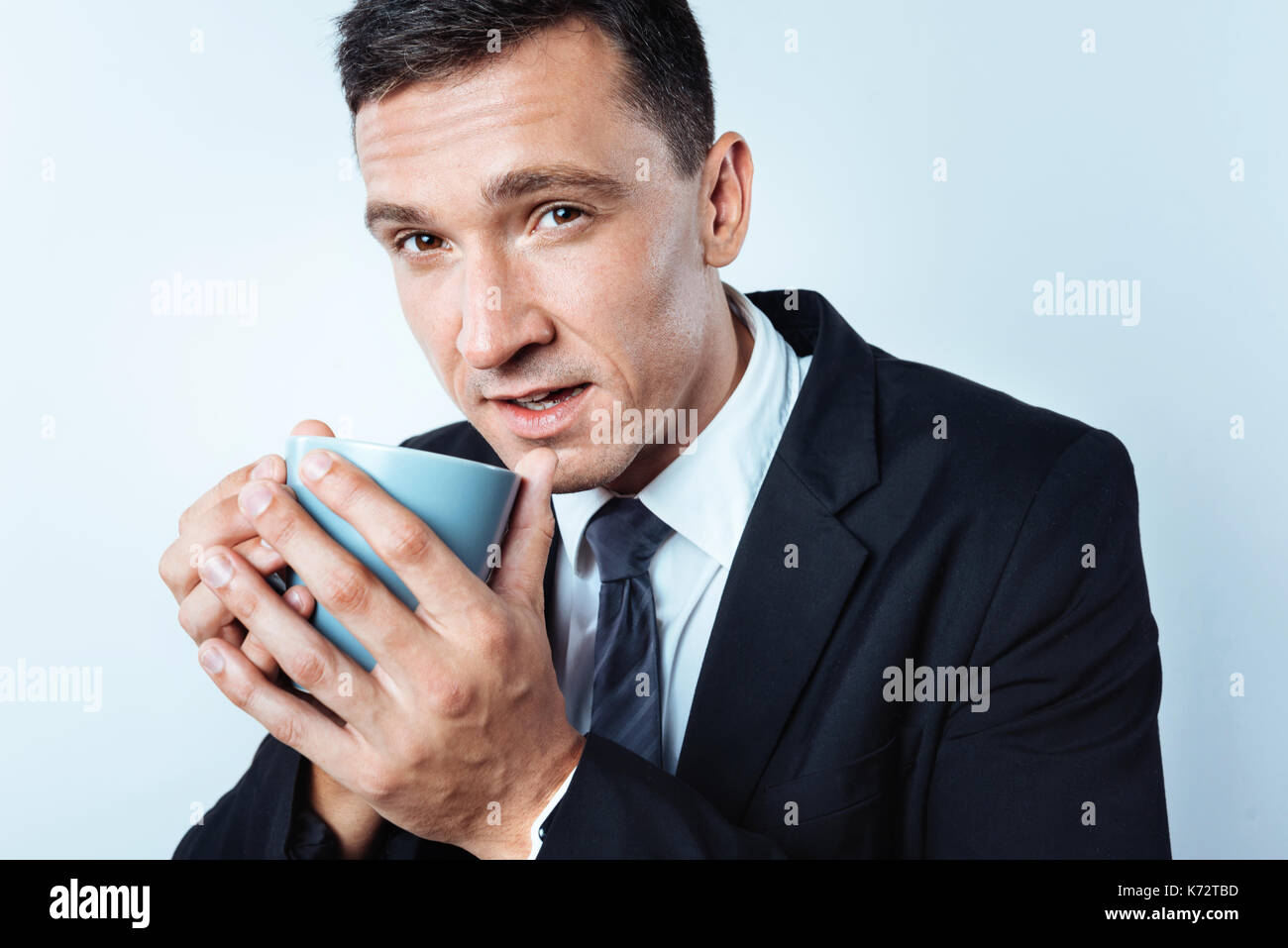 Close up of cold man in black suit drinking coffee Stock Photo - Alamy