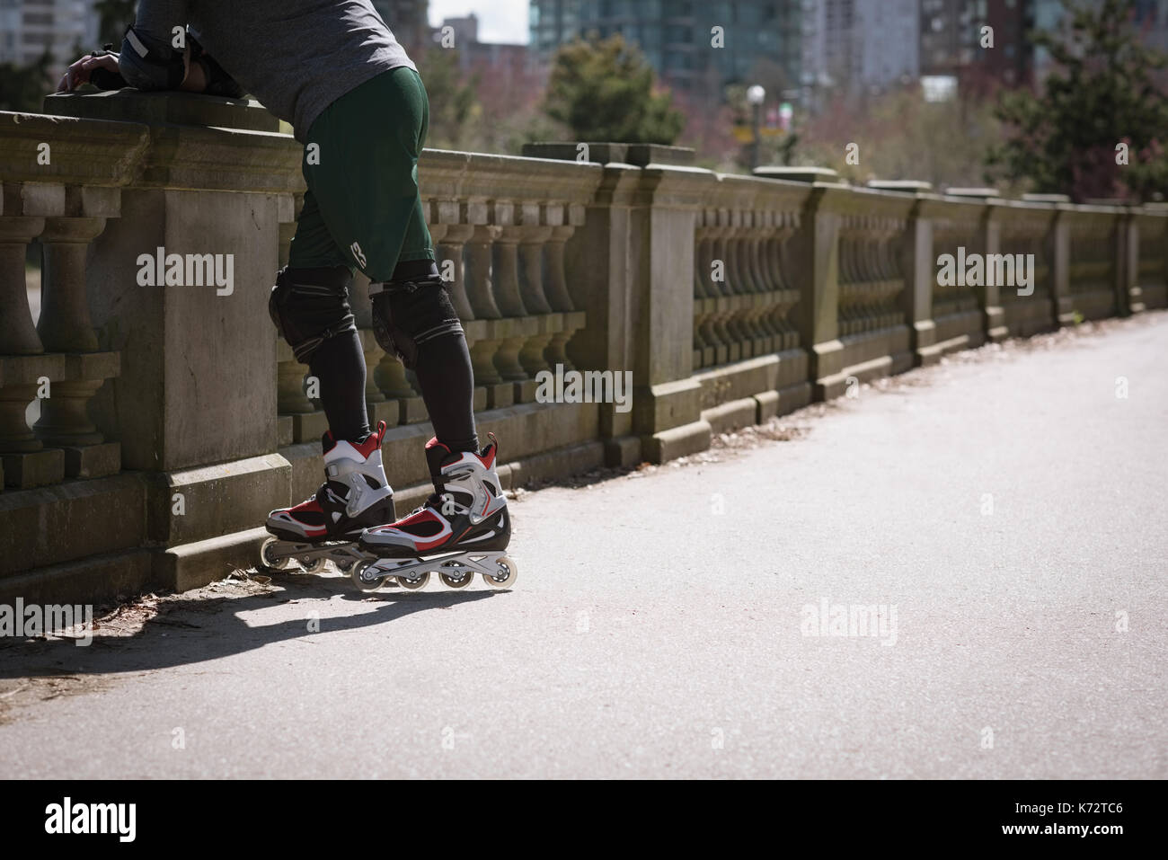 Side view of man wearing roller skates standing by railing during sunny ...