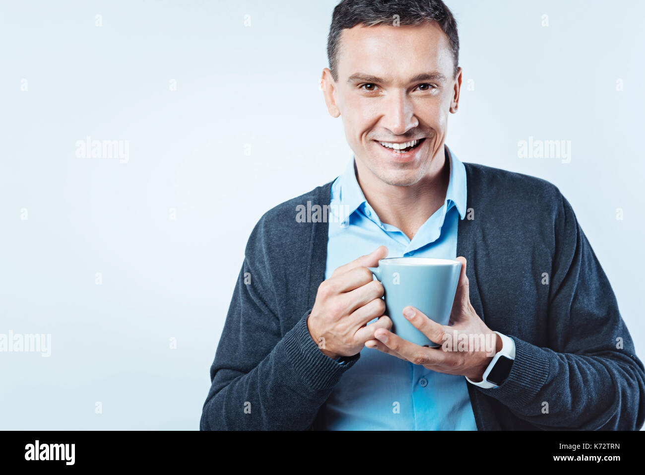 Cheerful man with cup of coffee beaming for camera Stock Photo - Alamy