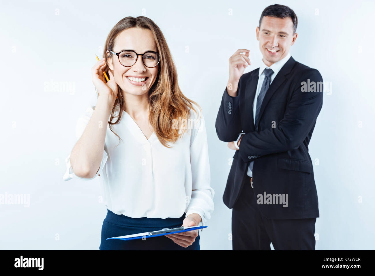 Attractive businesswoman with clipboard smiling into camera Stock Photo ...