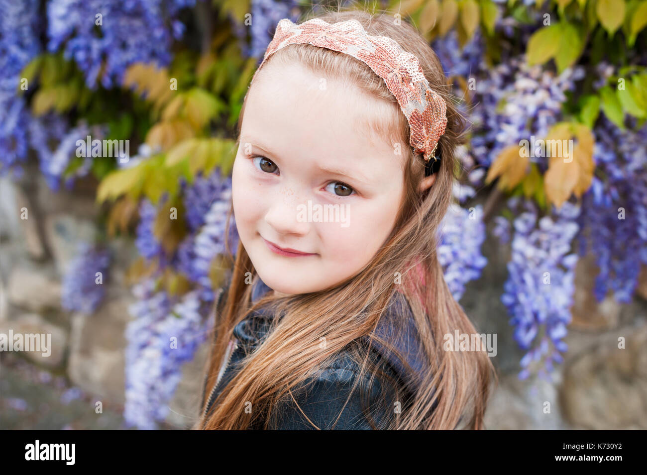 Spring portrait of cute kid girl with wisteria flowers on background ...