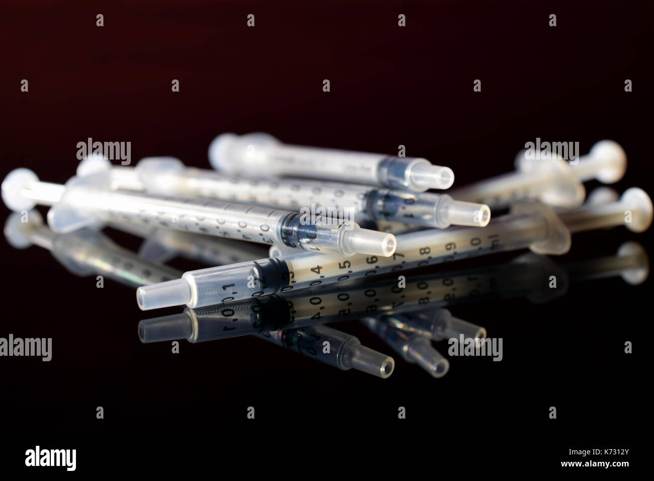 Pile of syringes on black reflective surface Stock Photo - Alamy
