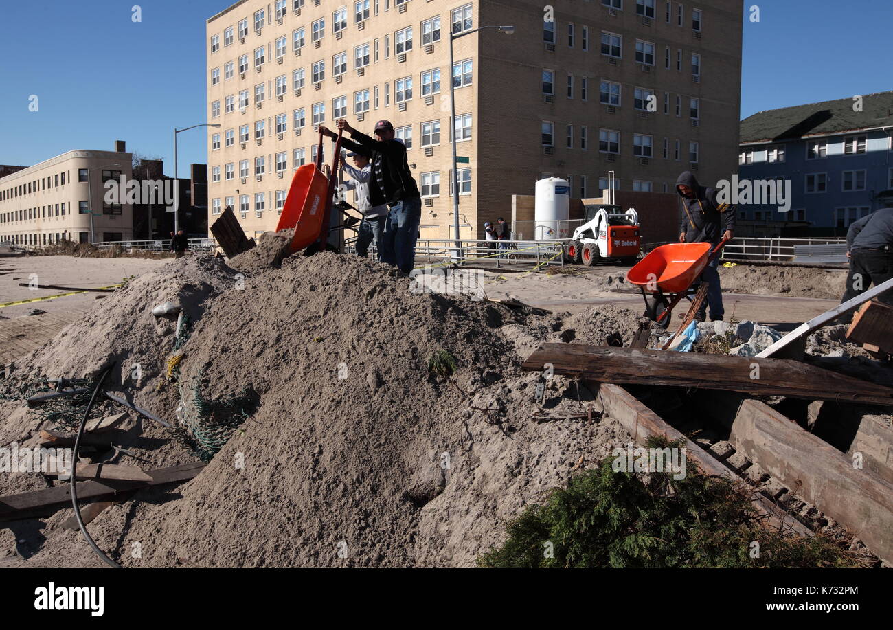Laborers remove sand from the destroyed boardwalk in the aftermath of ...