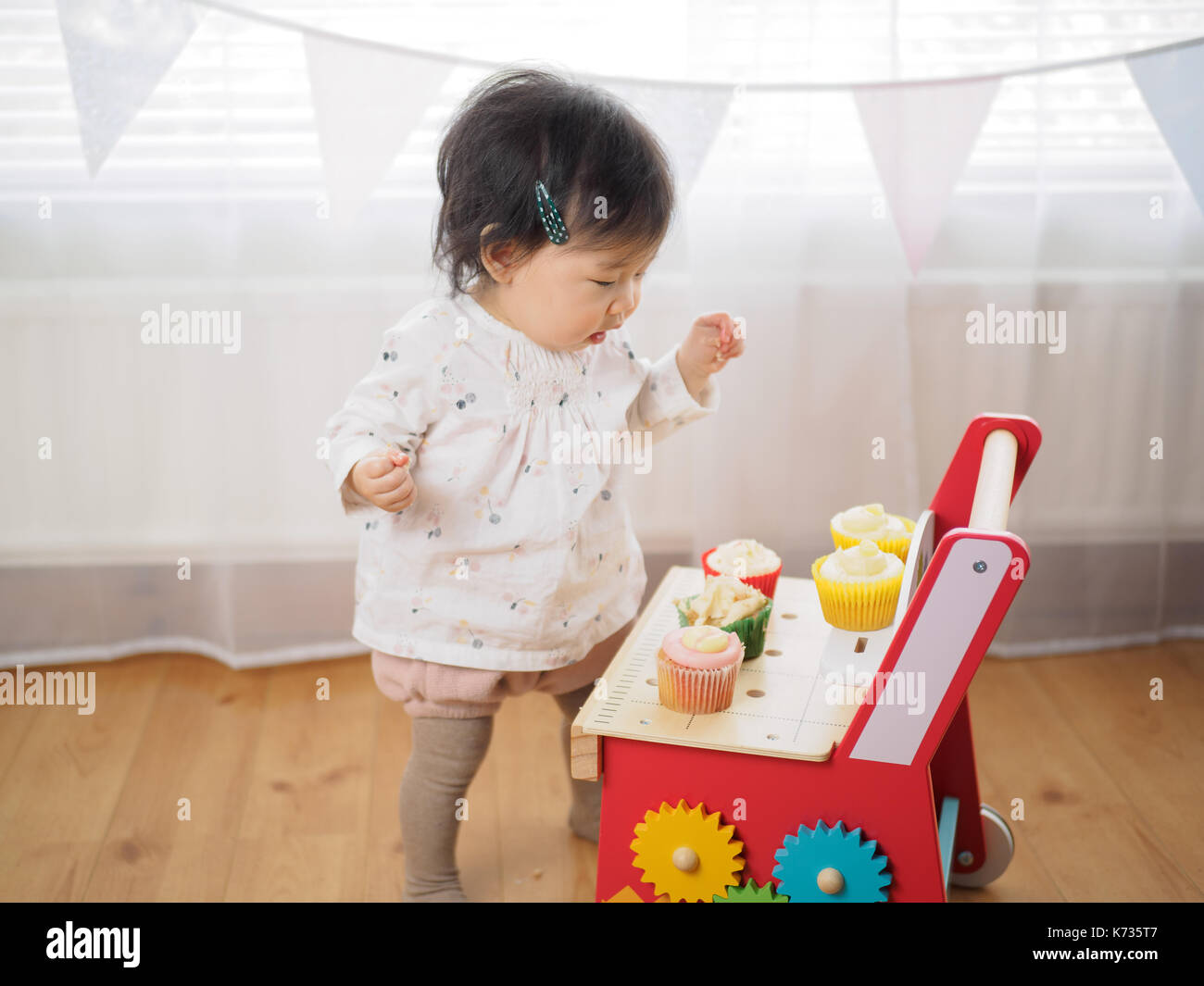 baby girl eating cup cake at home Stock Photo - Alamy