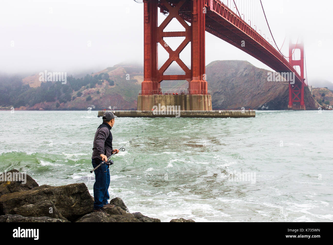 A fisherman fishing in Fort Point with the Golden Gate Bridge on the ...