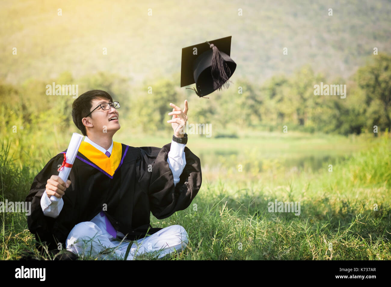 Graduation: Student sit and smile throwing graduation hat with Diploma ...