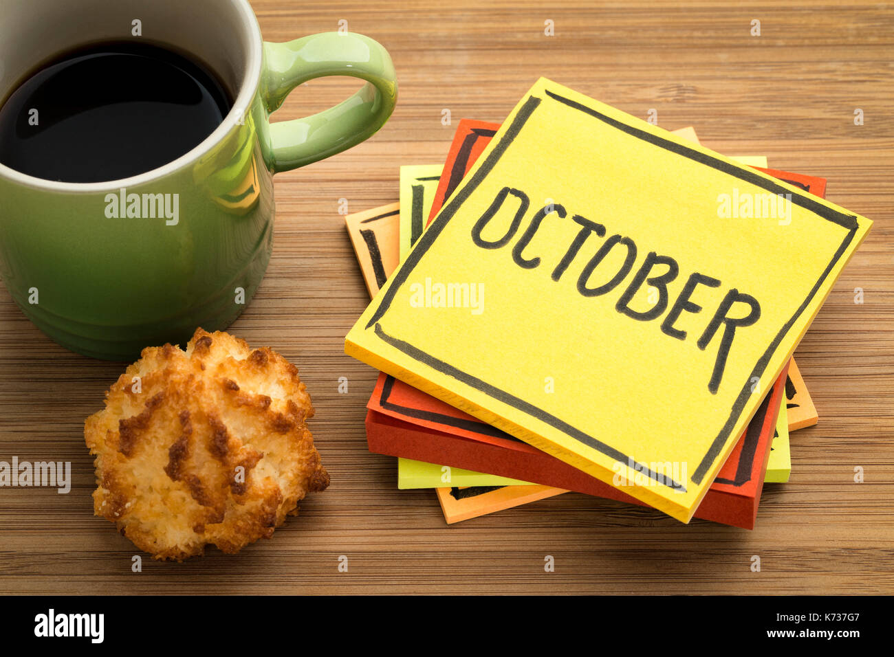 October reminder - handwriting in black ink on a sticky note with a cup ...