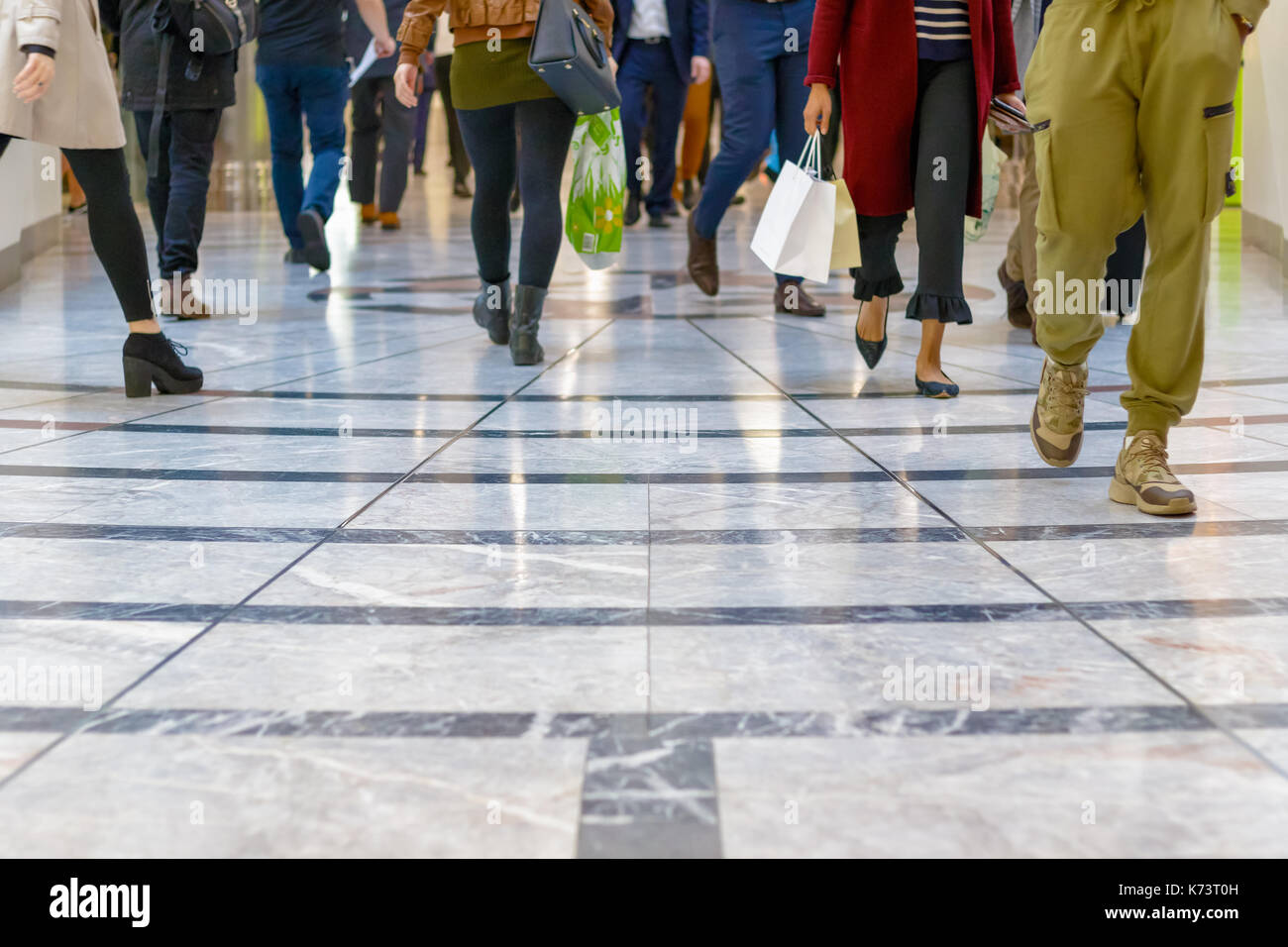 A modern floor with legs of a crowd walking in a shopping mall in the ...