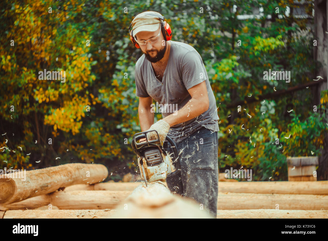 Man cutting piece of wood with chain saw Stock Photo - Alamy