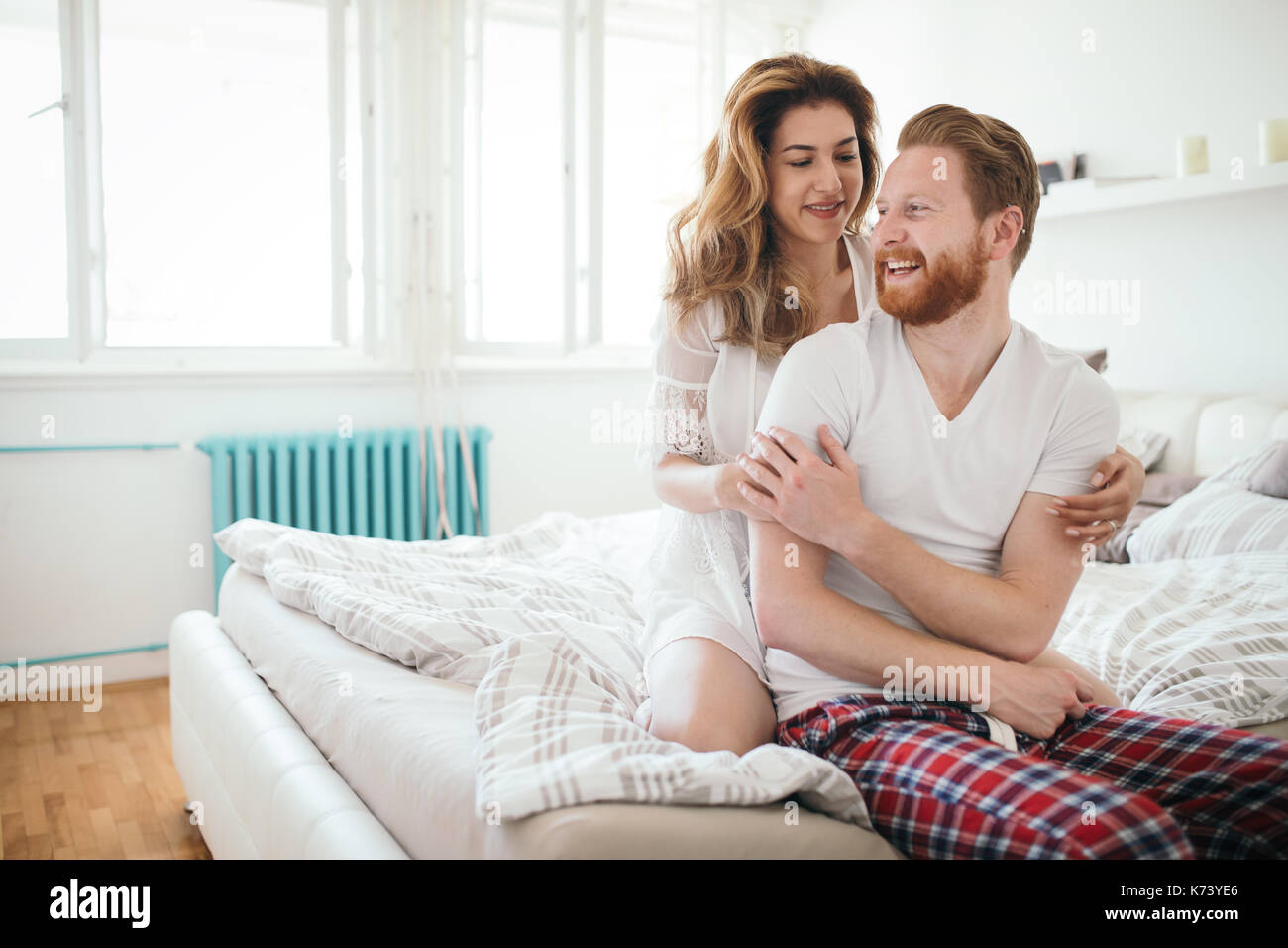 Beautiful happy couple waking up smiling in bedroom Stock Photo - Alamy