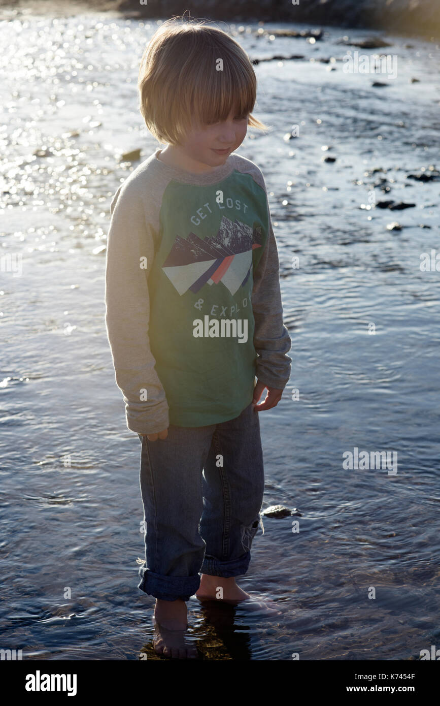 Boy standing in running sea water on the beach in Woolacombe, Devon ...