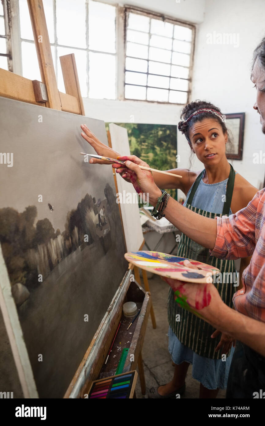Man assisting woman in painting during drawing class Stock Photo - Alamy