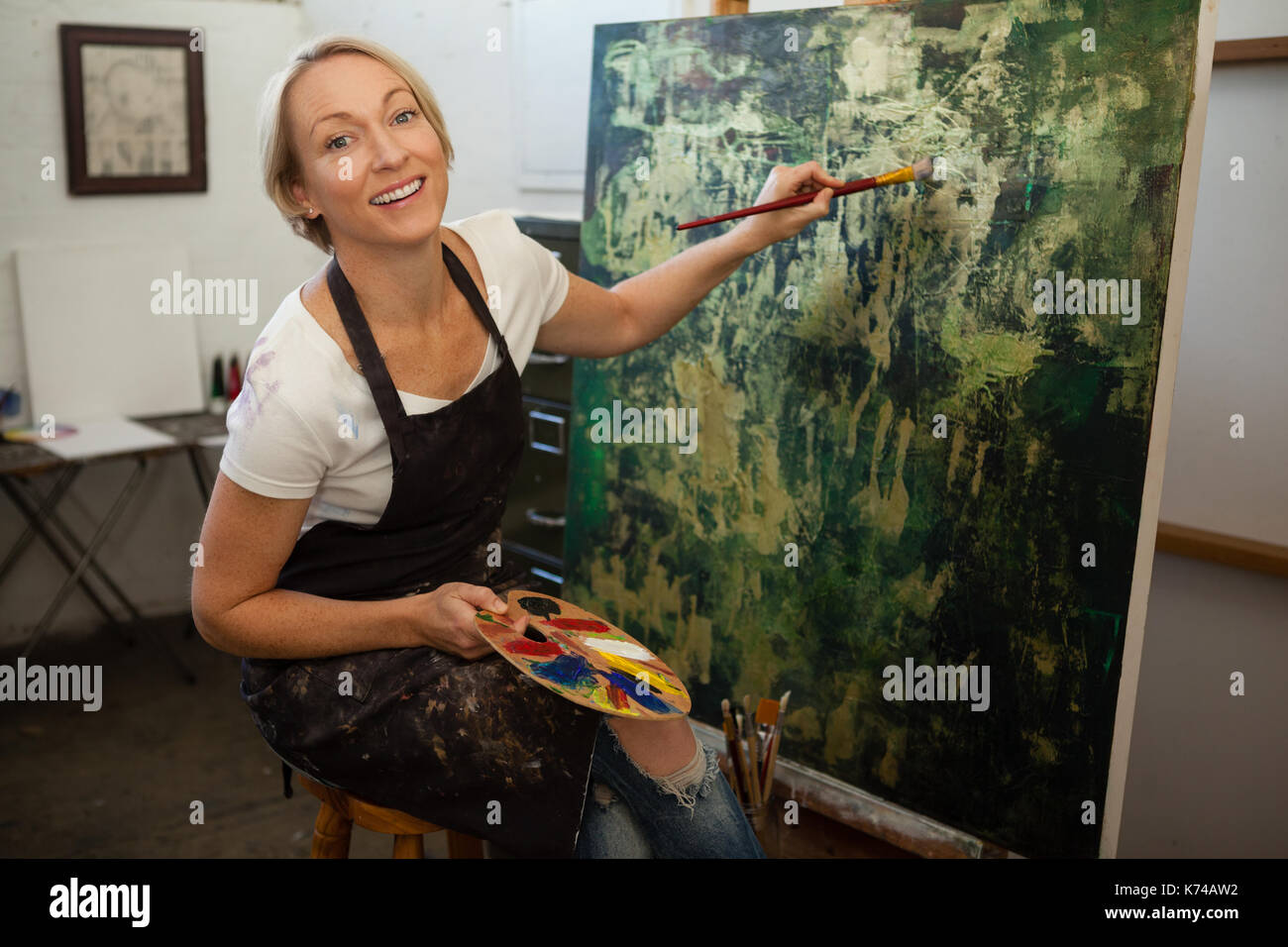Portrait of happy woman painting on canvas in drawing class Stock Photo ...