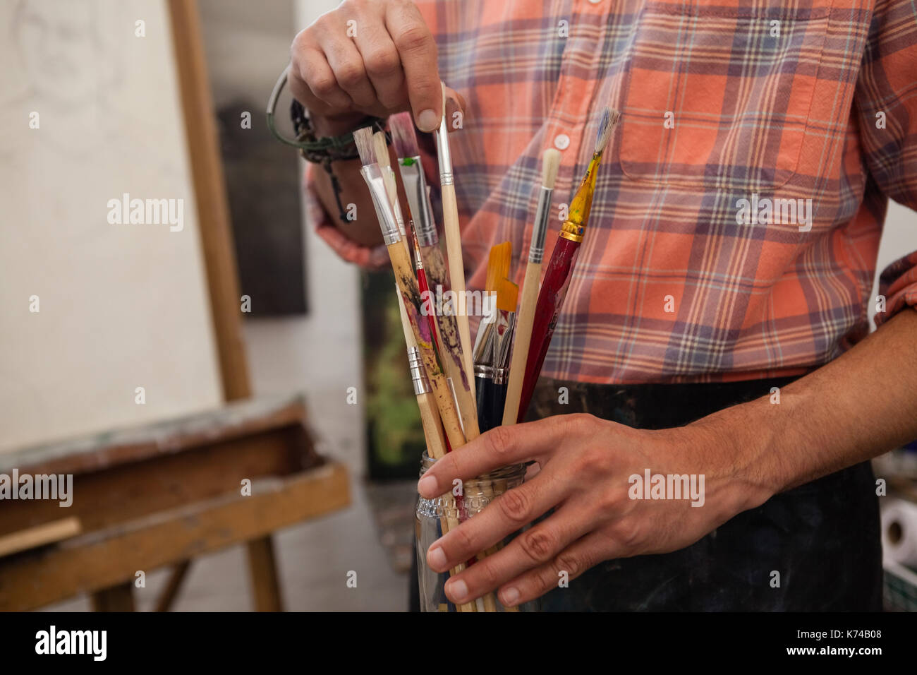 Man selecting a paintbrush in drawing class Stock Photo - Alamy