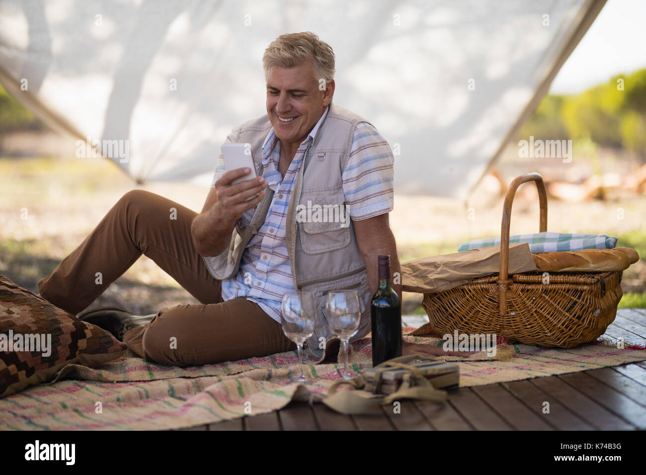 Happy man using mobile phone in cottage during safari vacation Stock ...