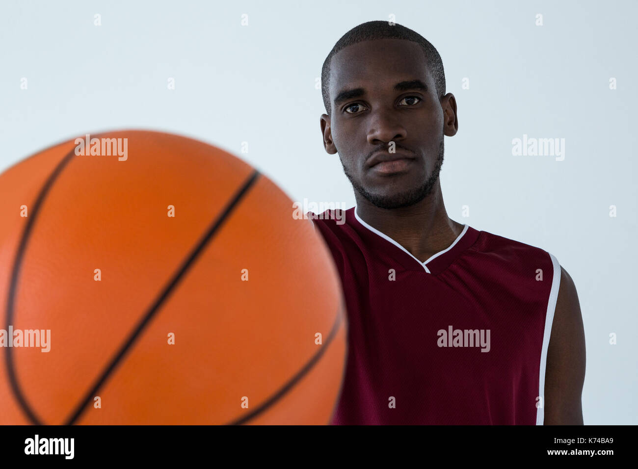 Confident player holding basketball against white background Stock ...