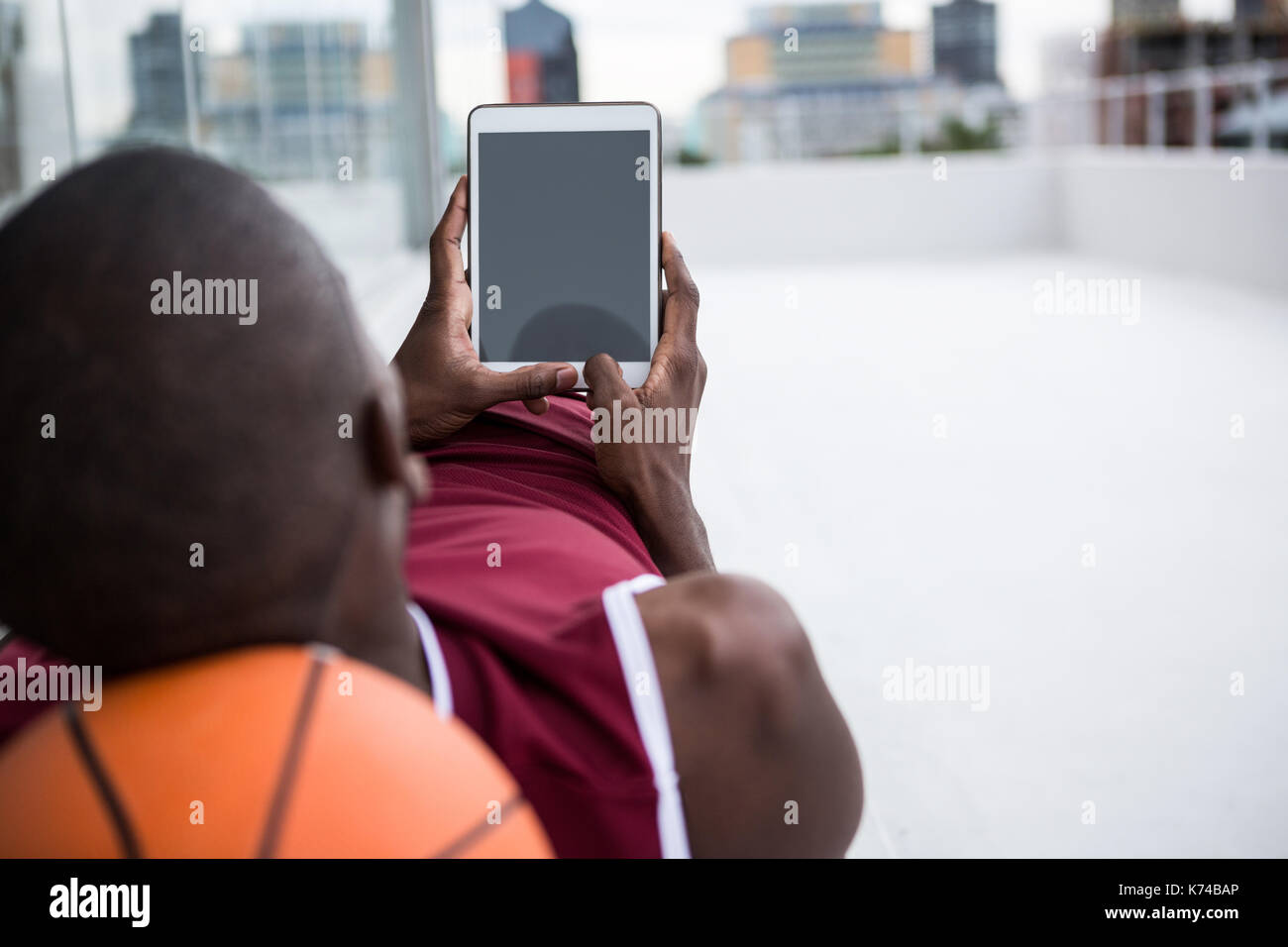 Basketball player using digital tablet while relaxing on terrace Stock ...